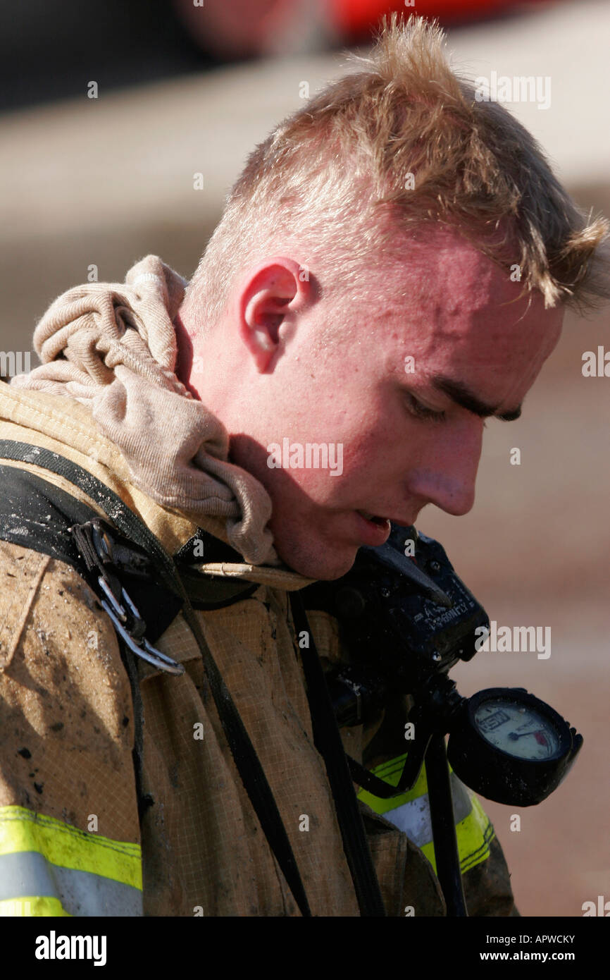 A young male firefighter full of debris is taking off his protective ...
