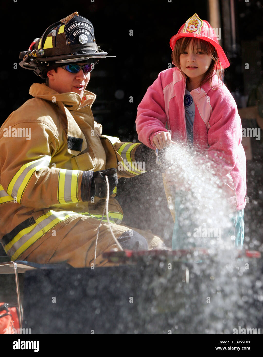 A Mequon Fire Department Firefighter and a young girl using a hoseline ...