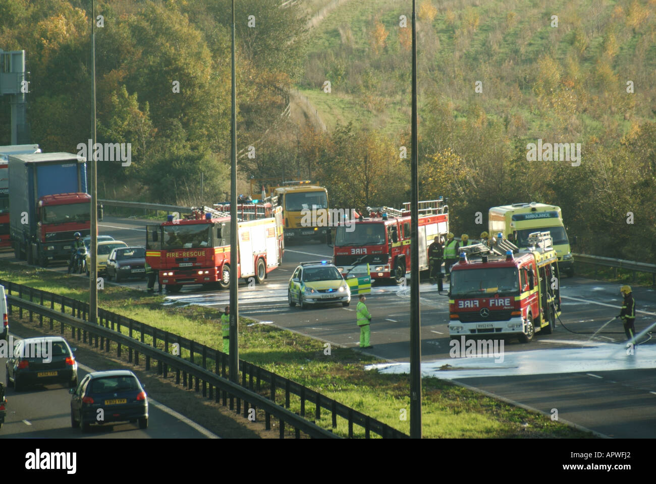 Firefighters hosing down motorway as fire engines and firefighters ...