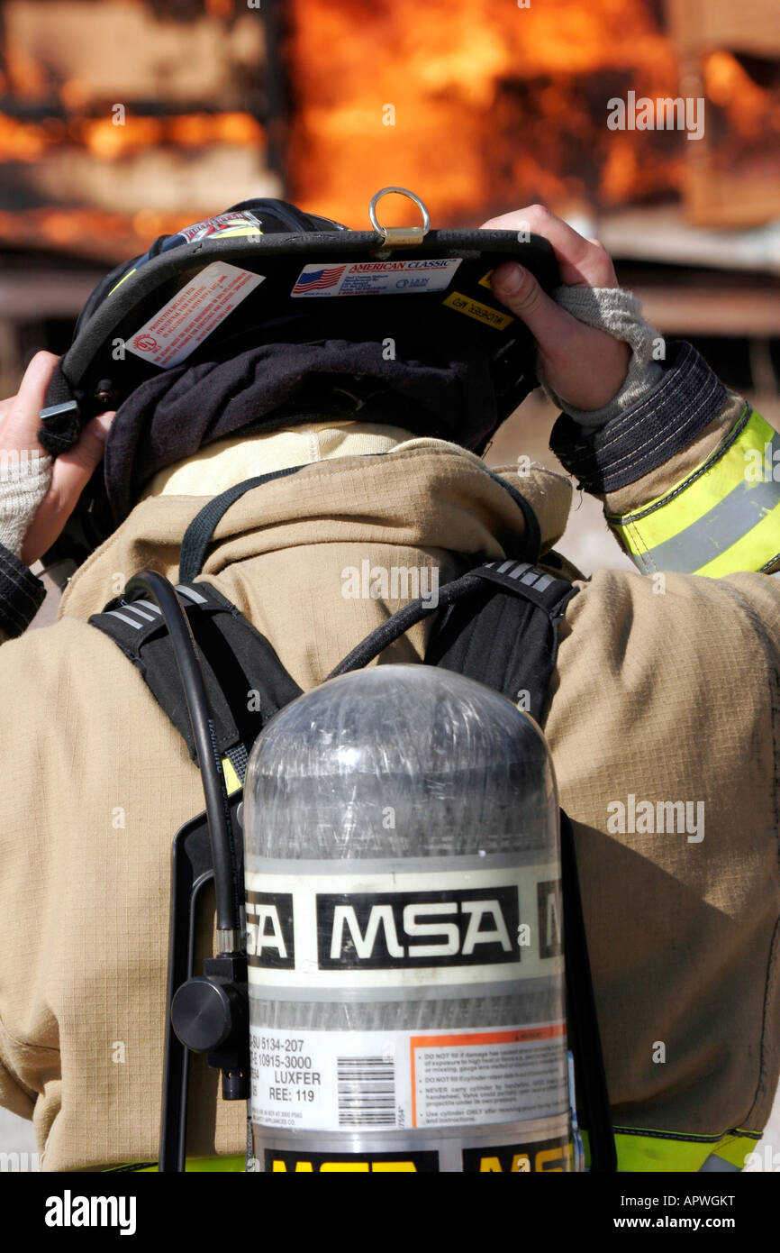 A firefighter putting on his helmet at the scene of a structure fire ...