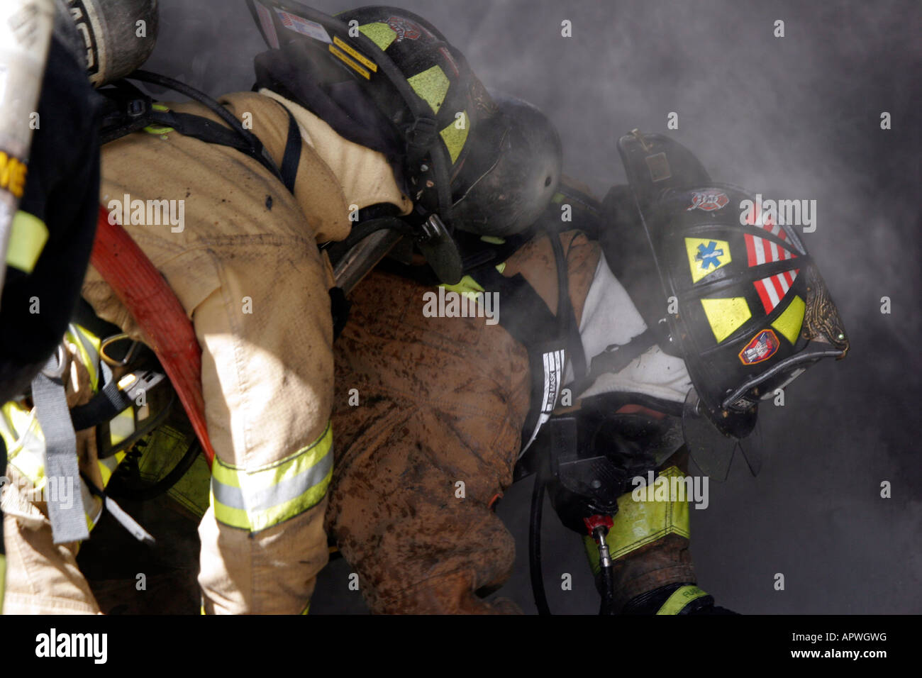 Two American firefighters taking a hoseline into the smoke to ...