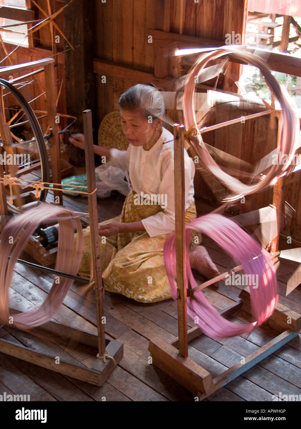 a woman sits spinning lotus threads into silk at Inle Lake in Myanmar ...