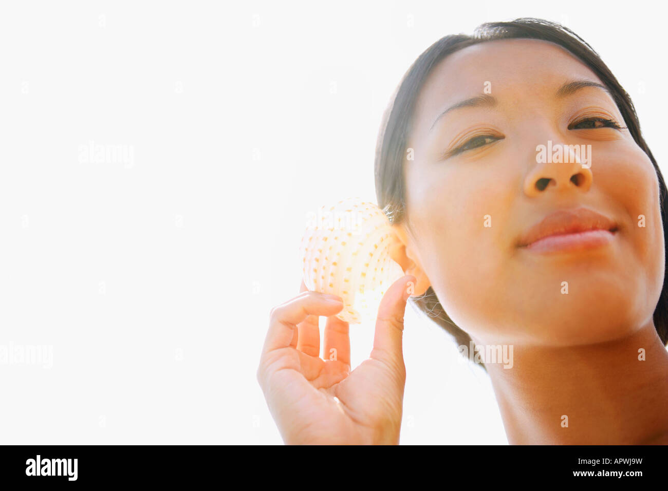 Woman holding seashell to ear hi-res stock photography and images - Alamy