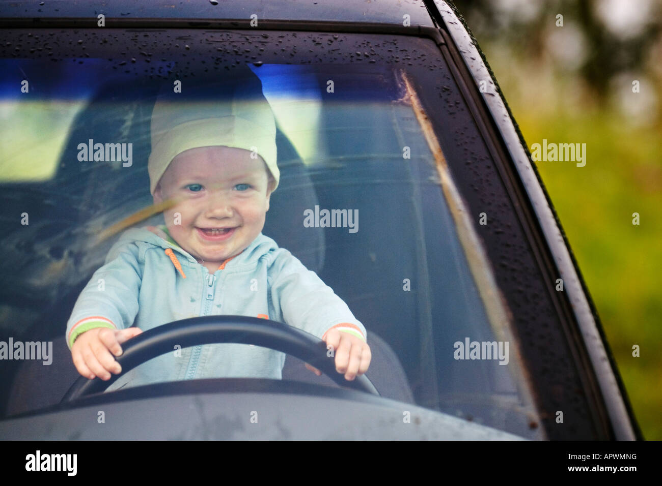 portrait of baby sitting behind steering wheel of car Stock Photo - Alamy