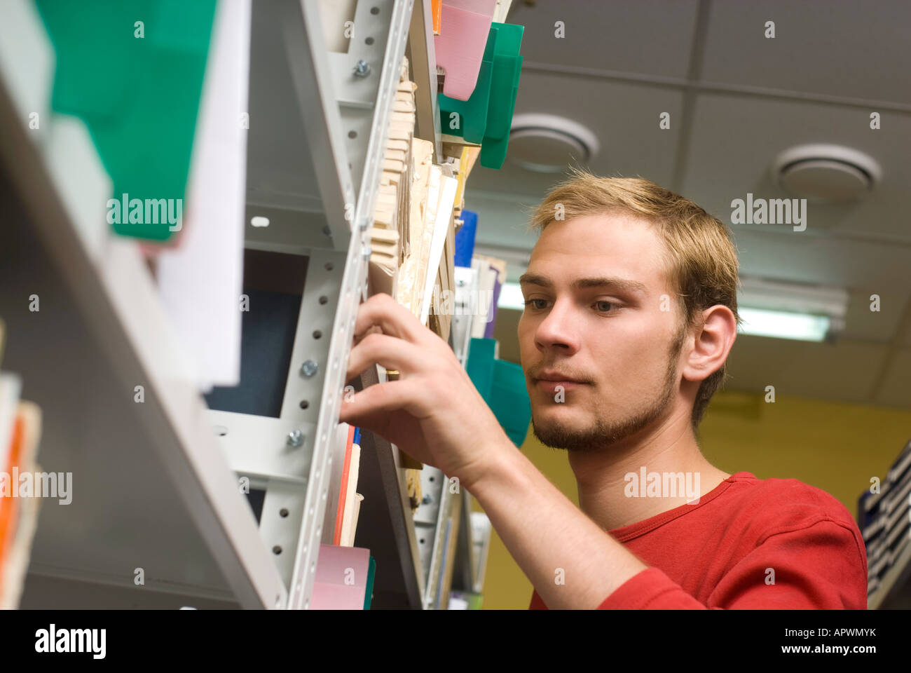 young student in library taking book from shelf Stock Photo - Alamy
