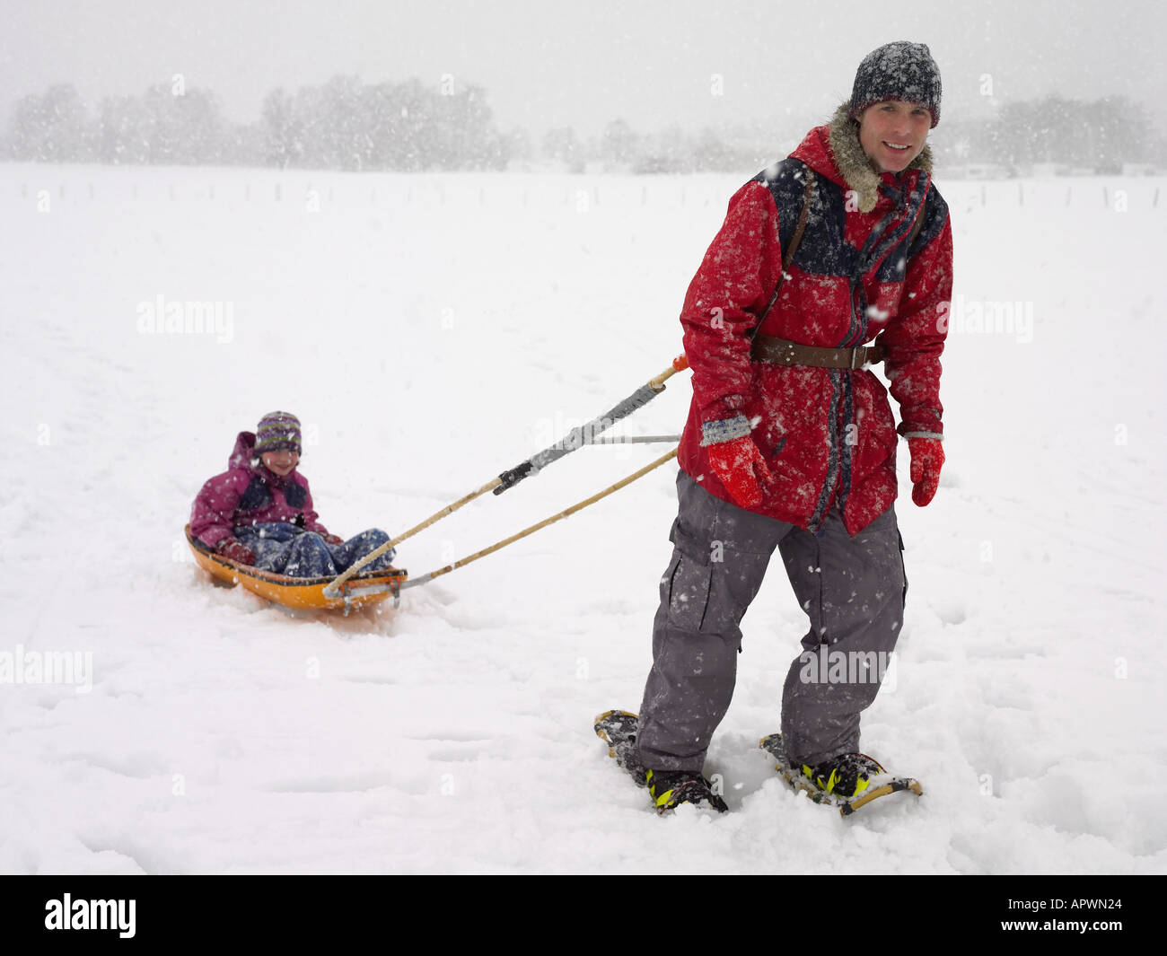 Man pulling his daughter in a sled Stock Photo - Alamy