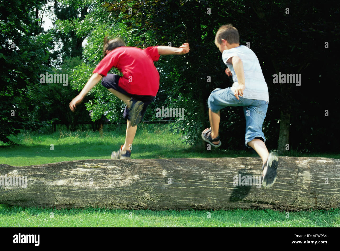 Boys jumping over a log Stock Photo - Alamy