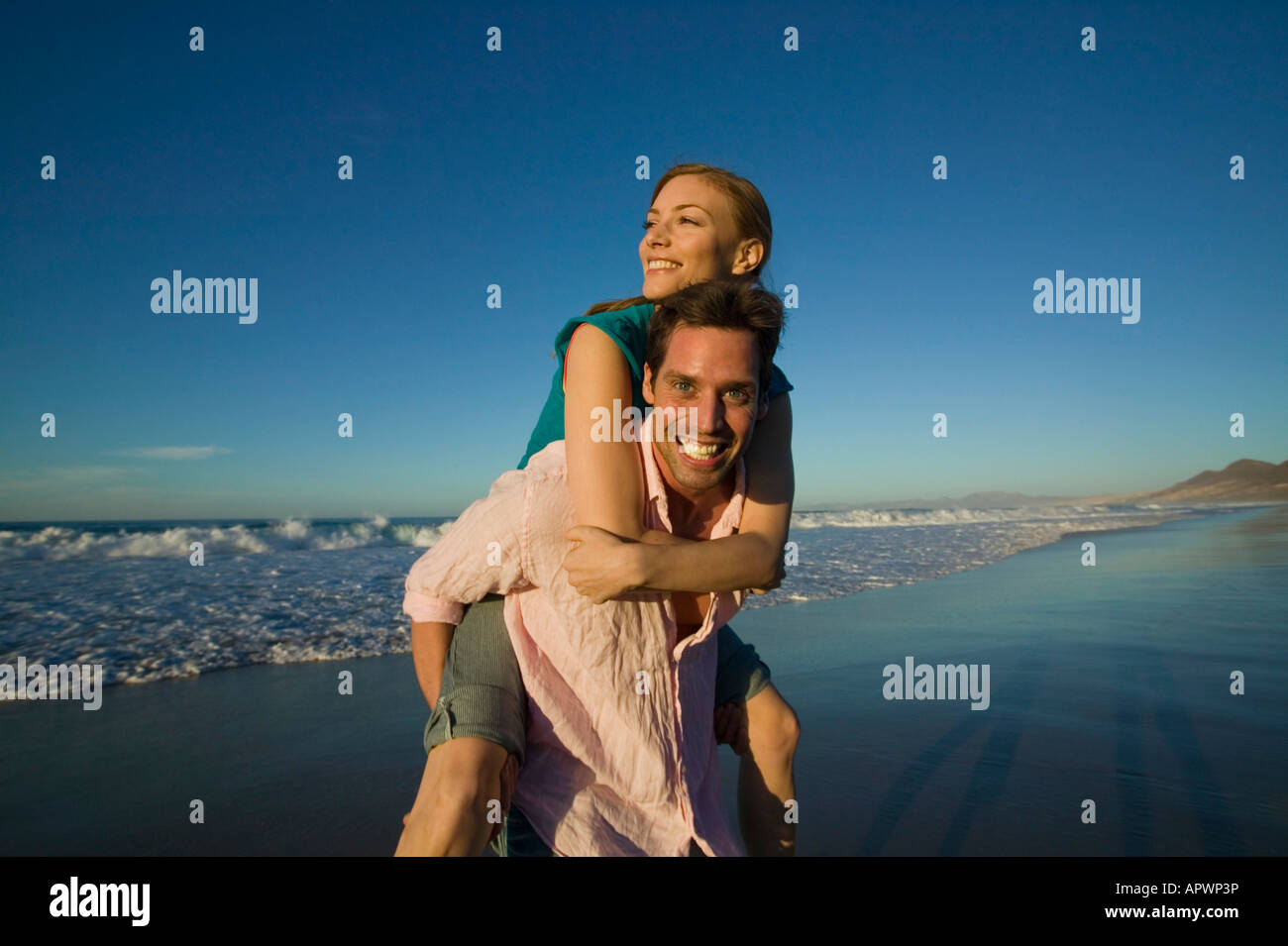 young man giving woman piggyback ride on beach Stock Photo - Alamy