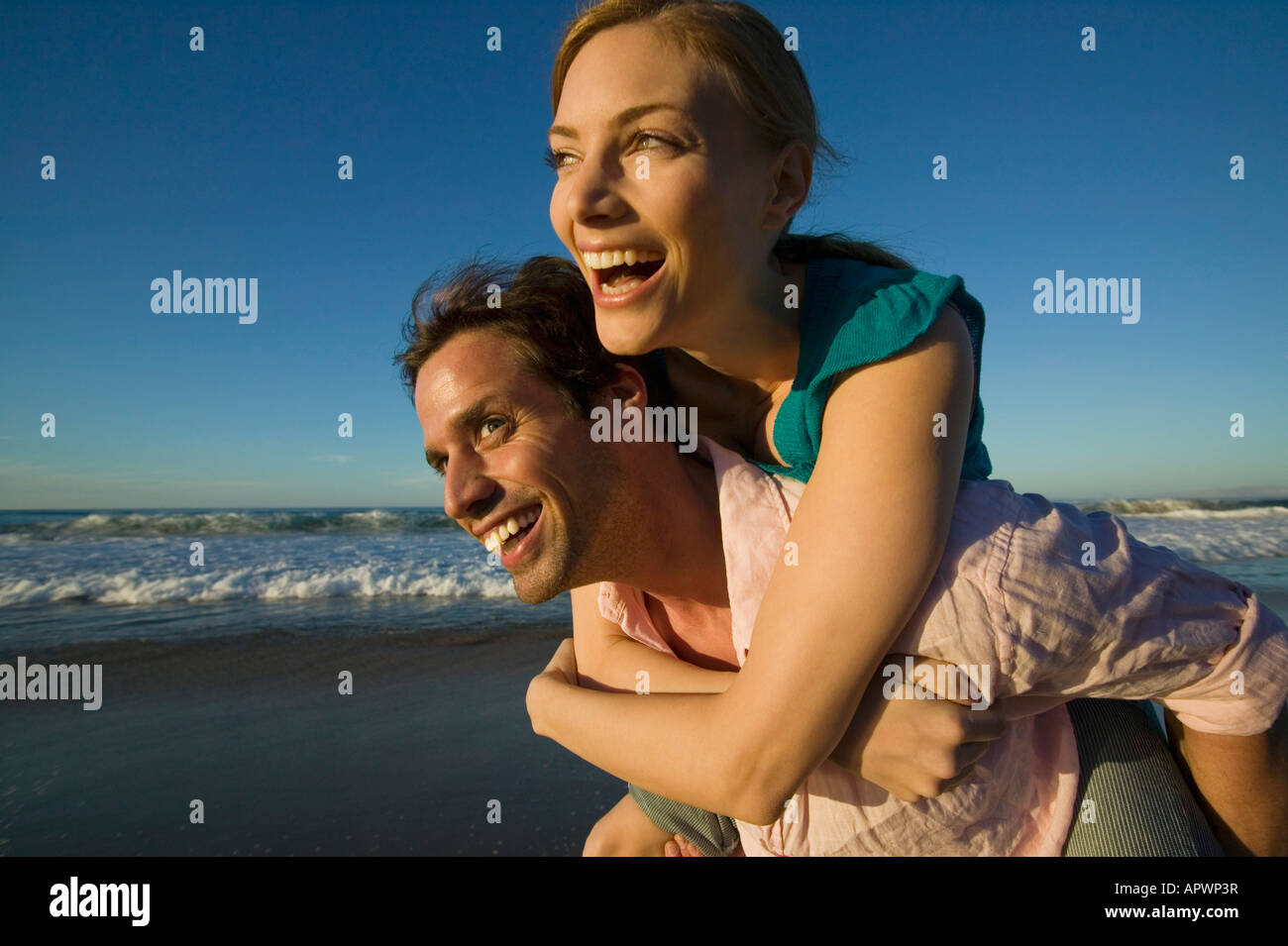 young man giving woman piggyback ride on beach Stock Photo - Alamy