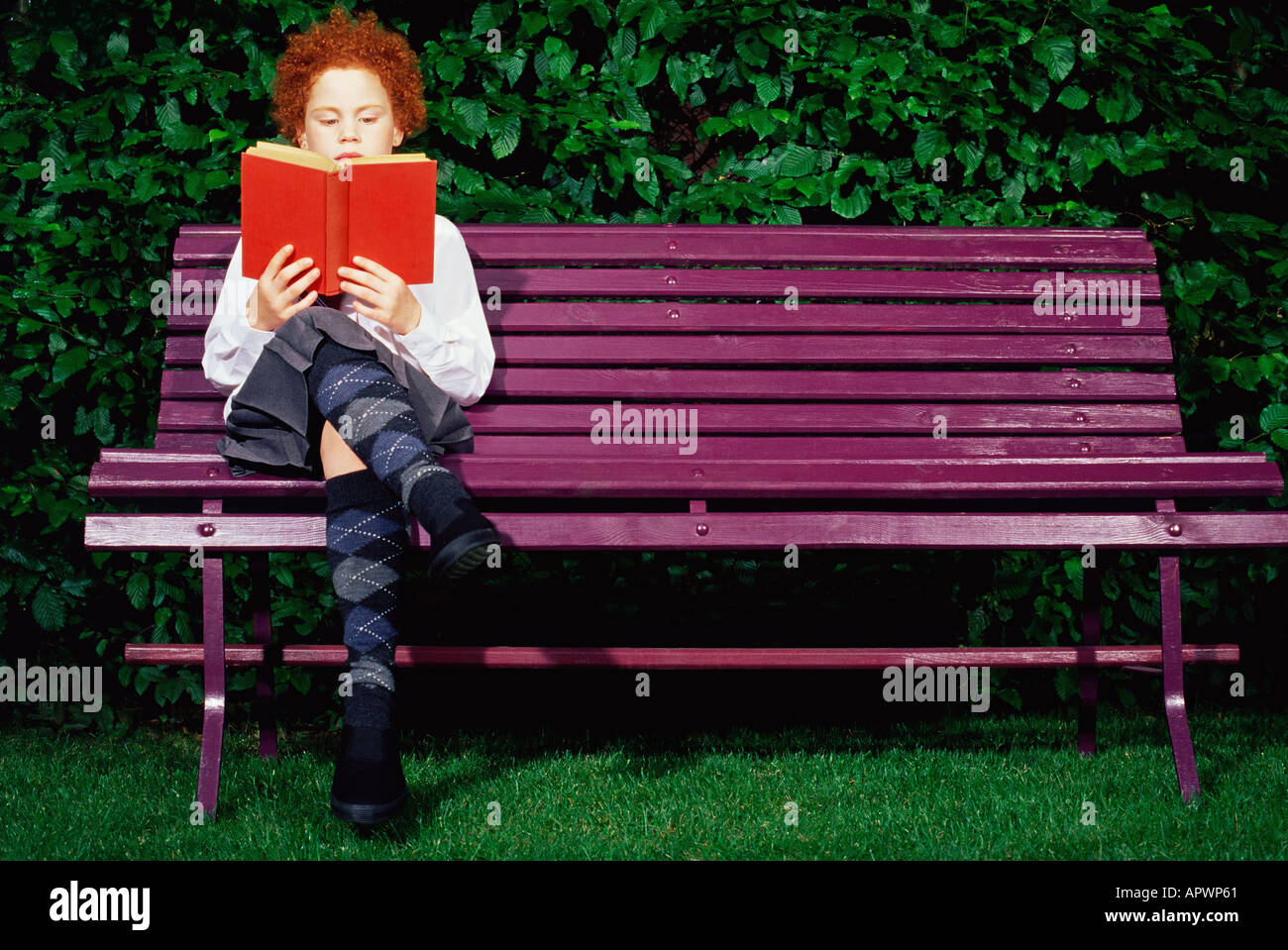 Girl on a bench reading a book Stock Photo - Alamy