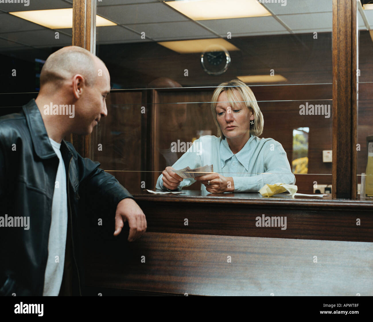 Betting shop worker counting money for customer Stock Photo - Alamy
