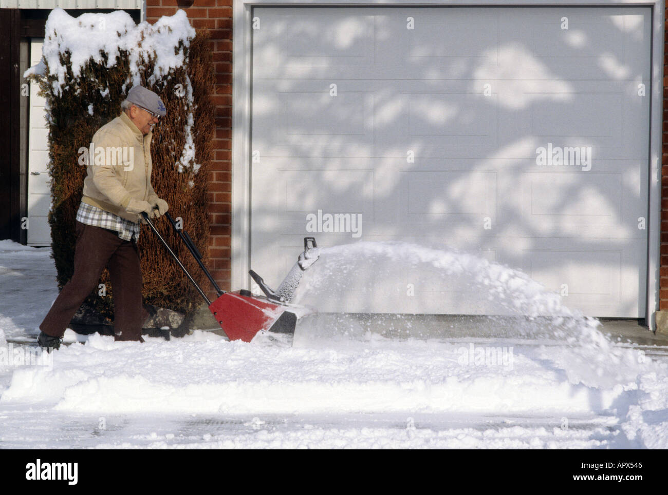 A man clearing snow from his driveway with snow blower Stock Photo - Alamy