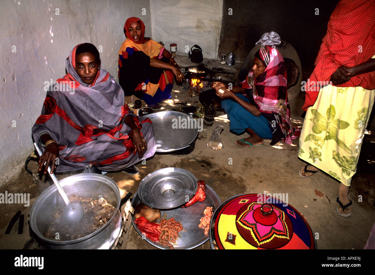 Three women share the cooking in a Nubian kitchen while a fourth woman ...