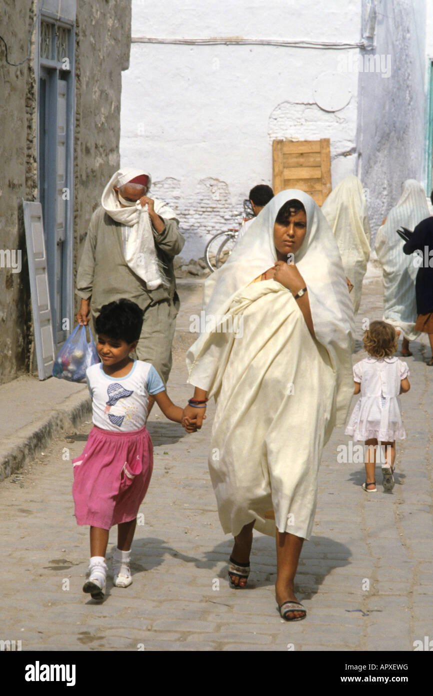 Woman wearing traditional robes walking with her daughter in an alley ...