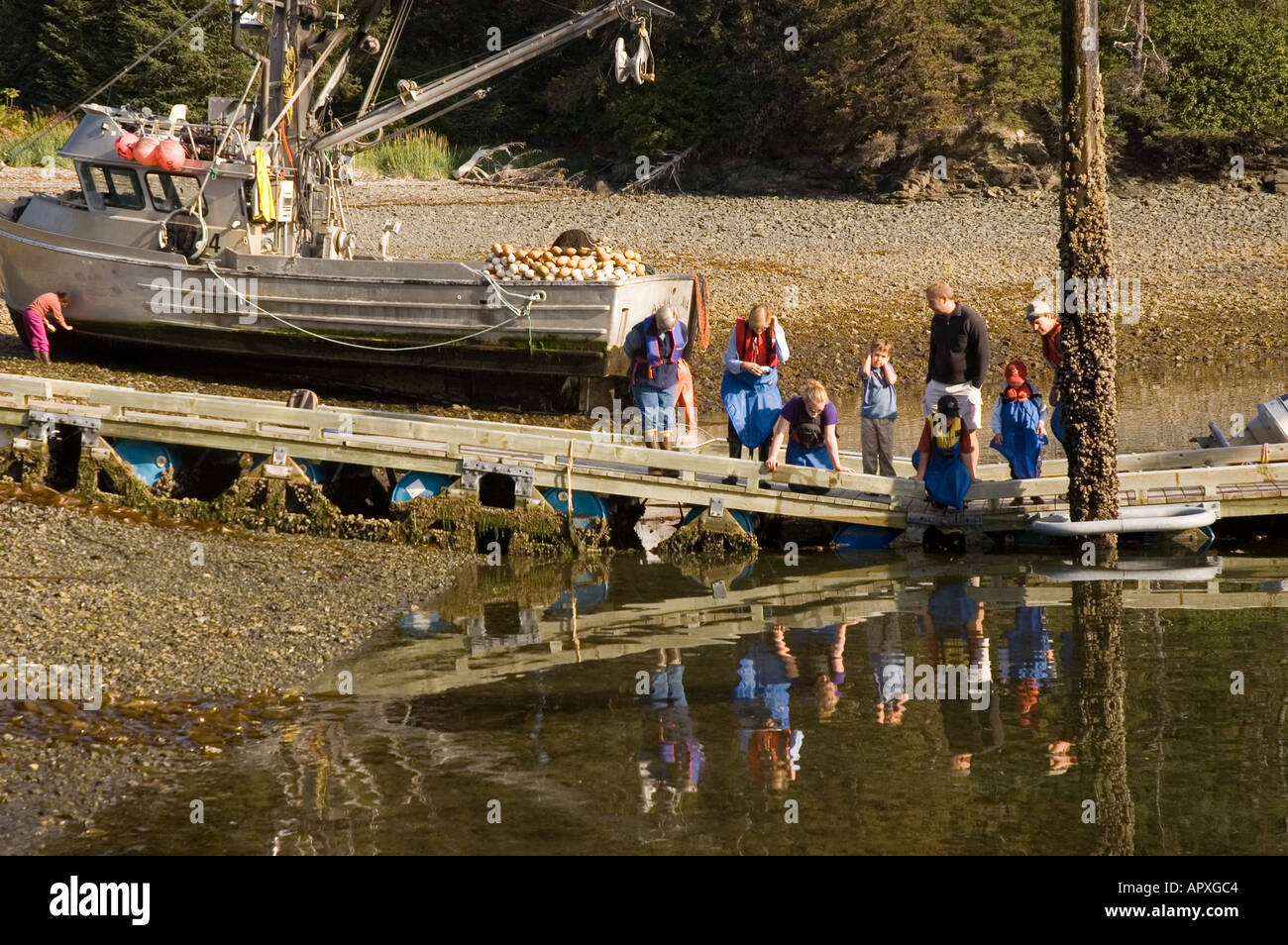 Family searching tide pool for sea creatures, fishing boat in back ...