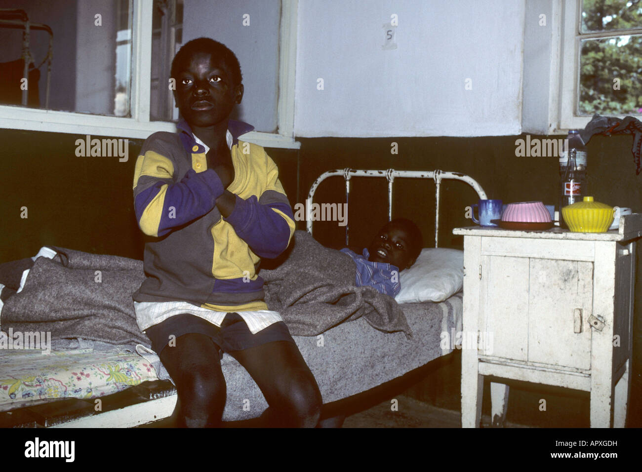 Young boy sitting on his brother's hospital bed at Livingstone hospital ...