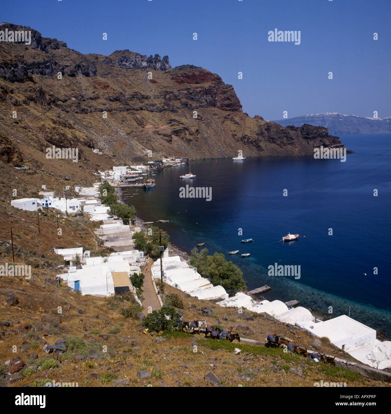 Looking down on Manolas harbour with donkeys on steep cliff path ...