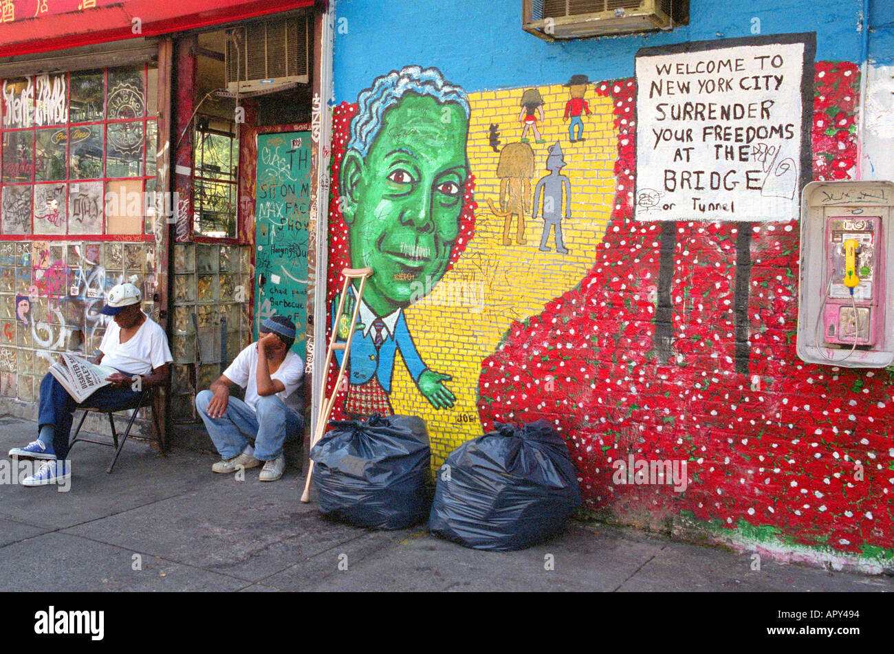 Homeless man sitting against graffiti wall on Manhattans lower Eastside ...
