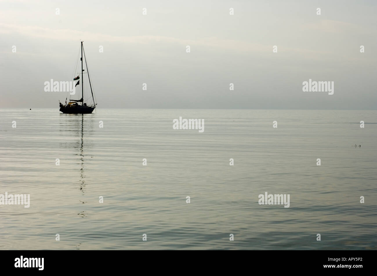 a sailing boat yacht at dusk over cardigan bay calm sea Aberystwyth ...