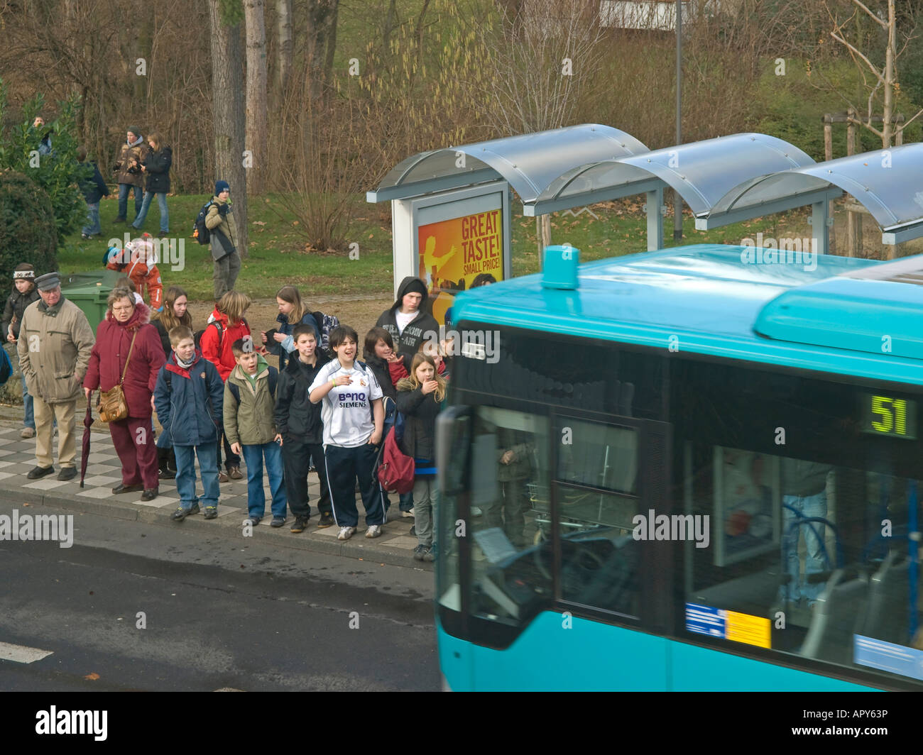 a few old people and a groupe of children standing at bus stop waiting ...