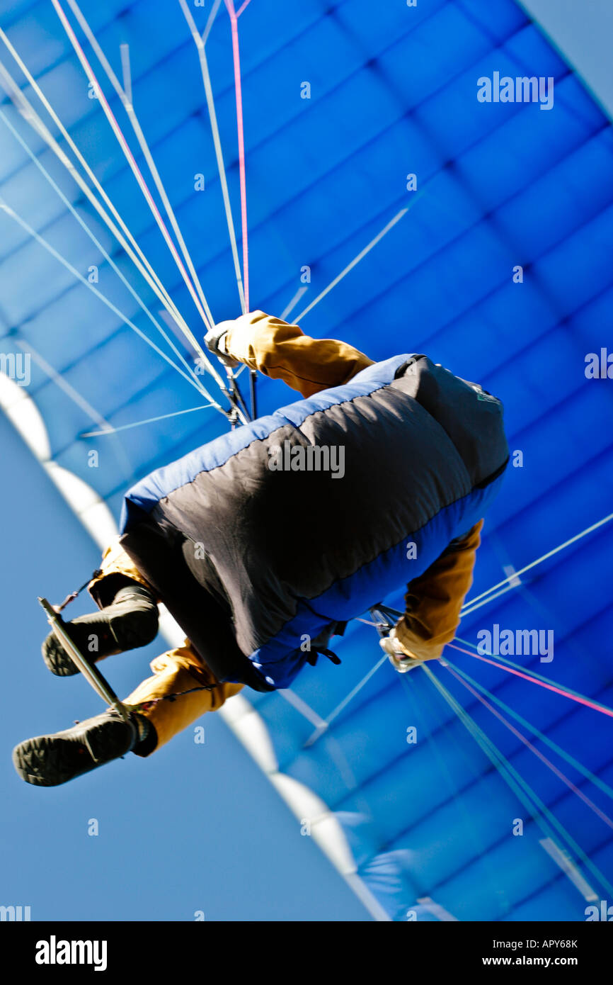 Blue canopy and harness of a paraglider seen from below against a deep ...