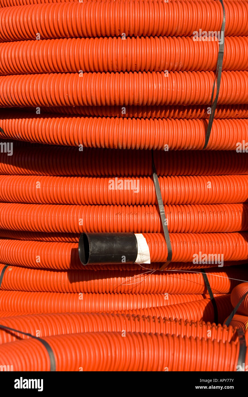 Image of a coiled up orange ribbed plastic tube on a building site ...