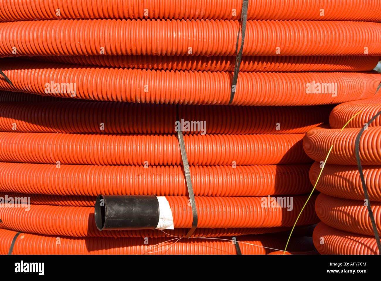 Image of a coiled up orange ribbed plastic tube on a building site ...