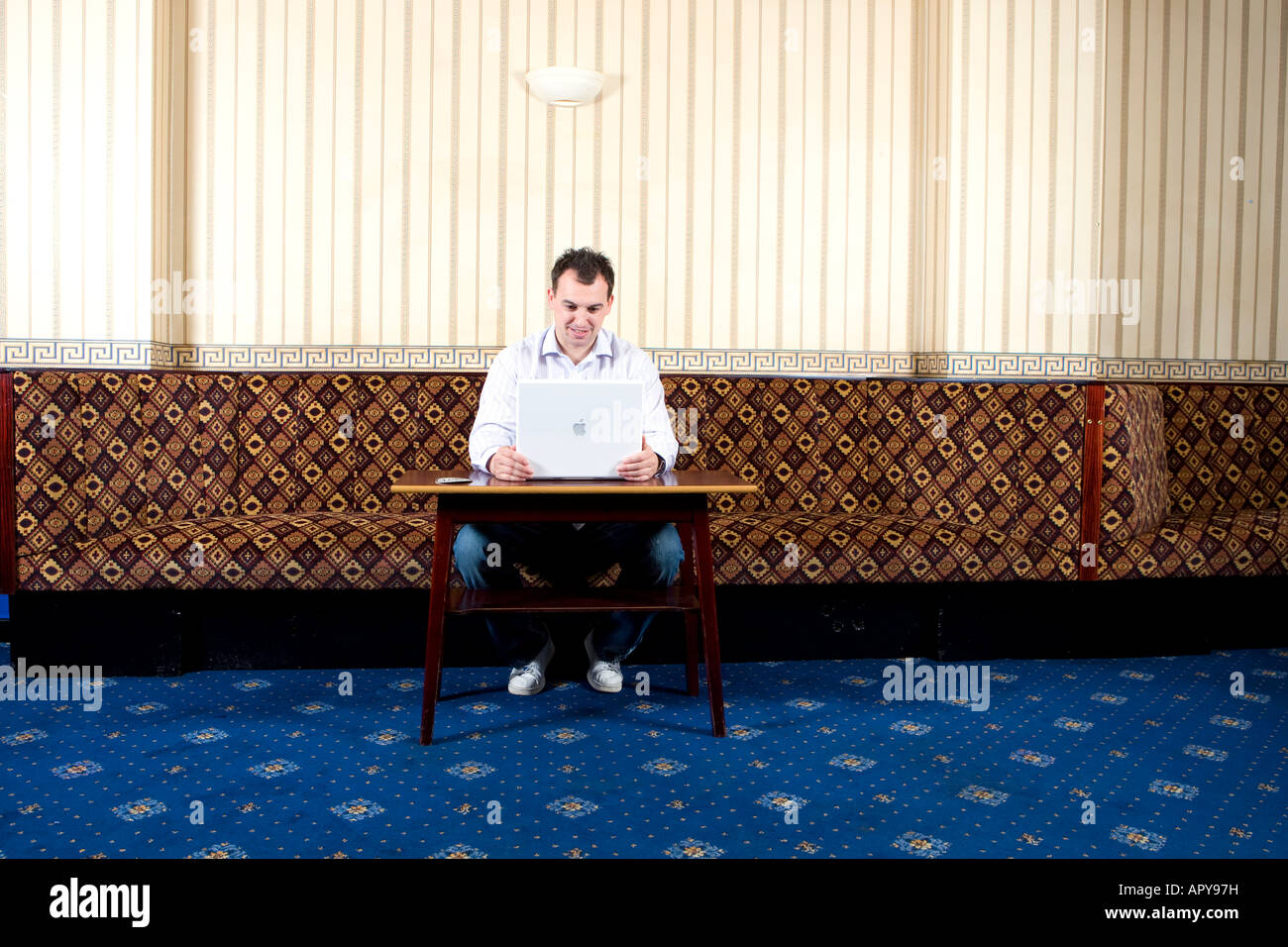 Man scratching head while looking apple mac laptop computer bar wall ...