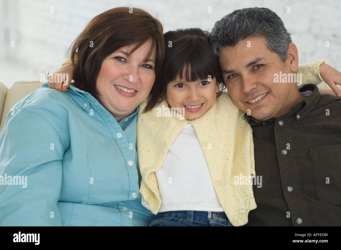 Hispanic parents and daughter hugging Stock Photo - Alamy