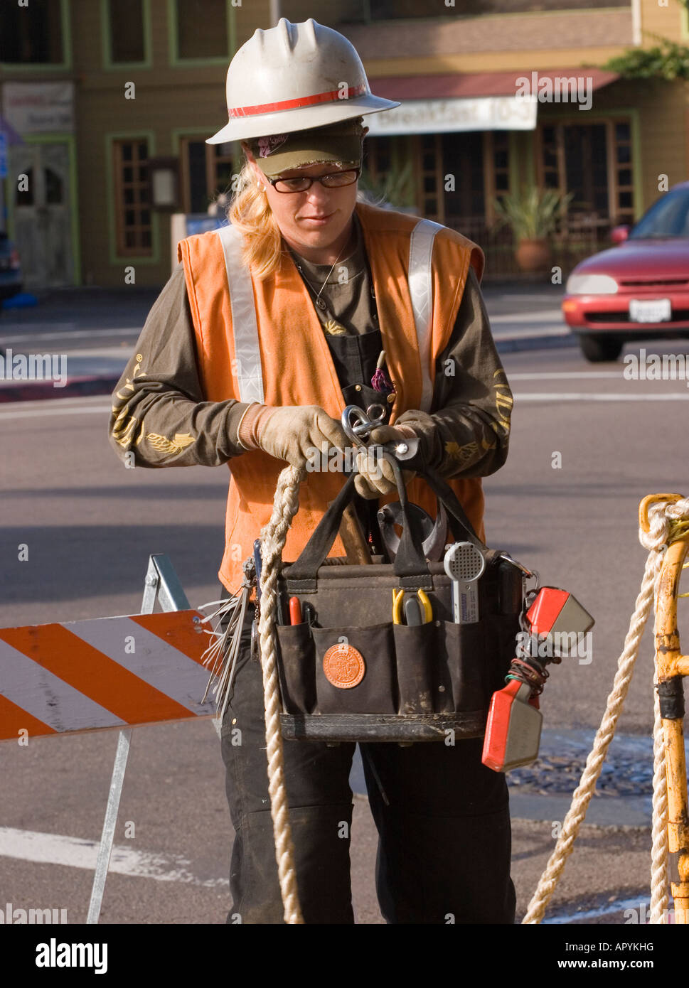 A young female utililty worker collects her tools after finishing her ...