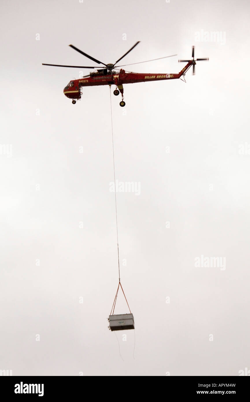 A sky crane helicopter in flight, carrying a heavy load for delivery ...