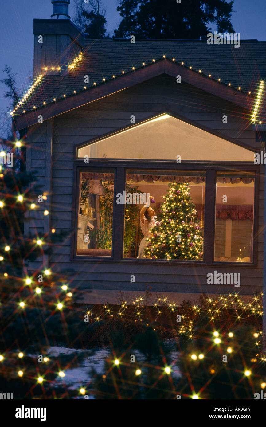 Woman decorates Christmas tree in home / thru window Stock Photo - Alamy