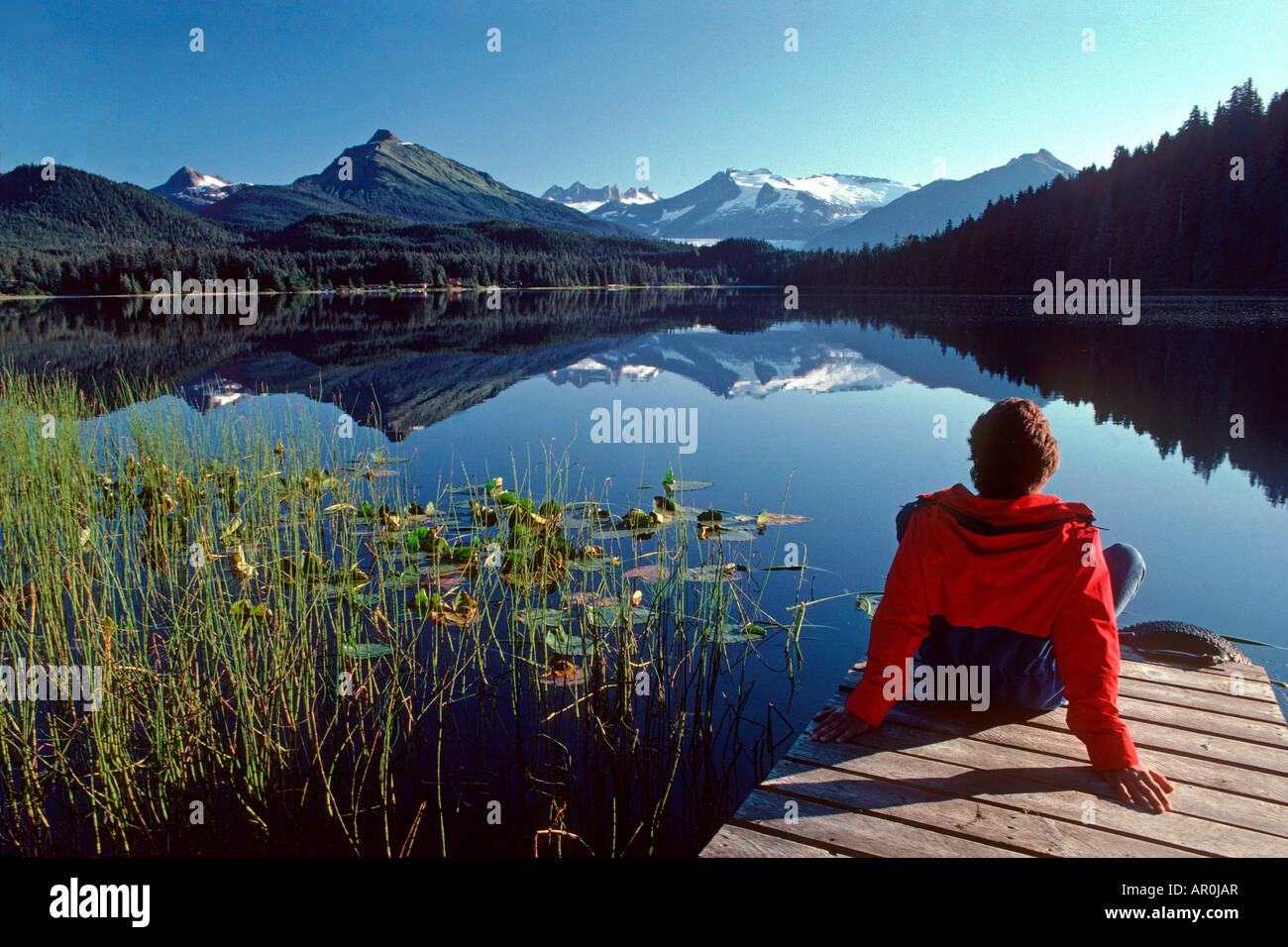 Man on dock Auke Lake Juneau Coast Mtns Southeast Alaska summer viewing ...