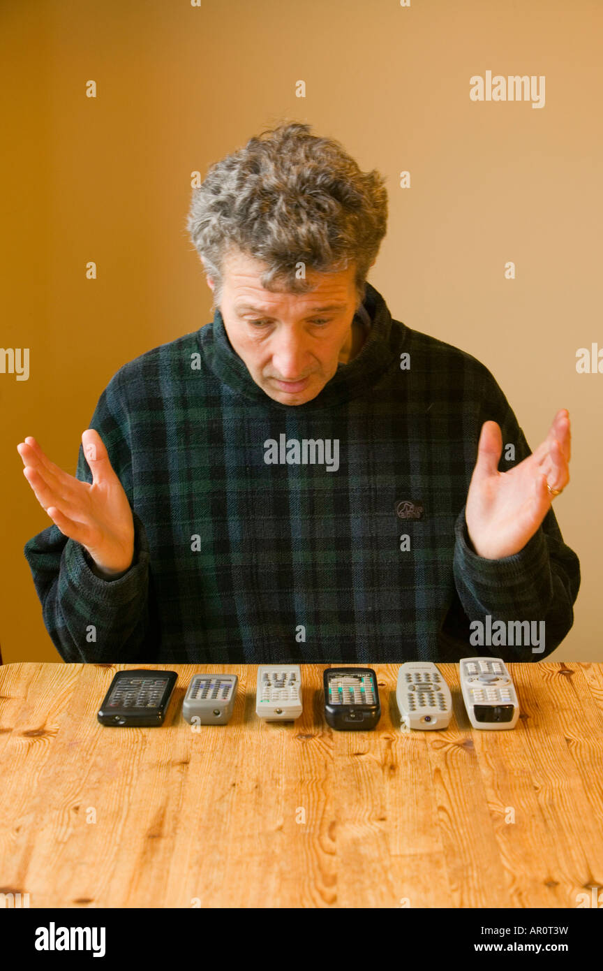 A man confused over which remote control to pick Stock Photo - Alamy