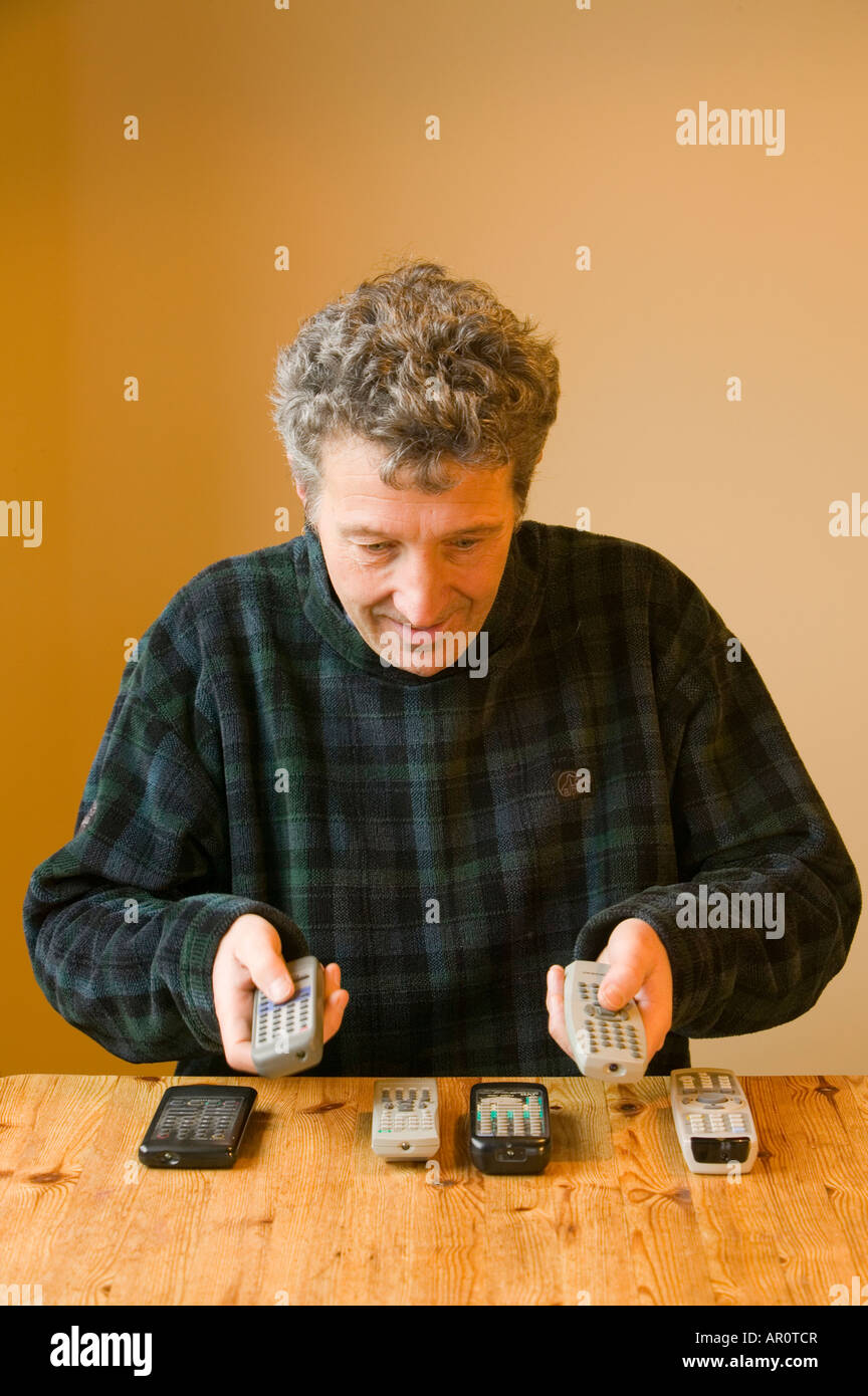 A man confused over which remote control to pick Stock Photo - Alamy