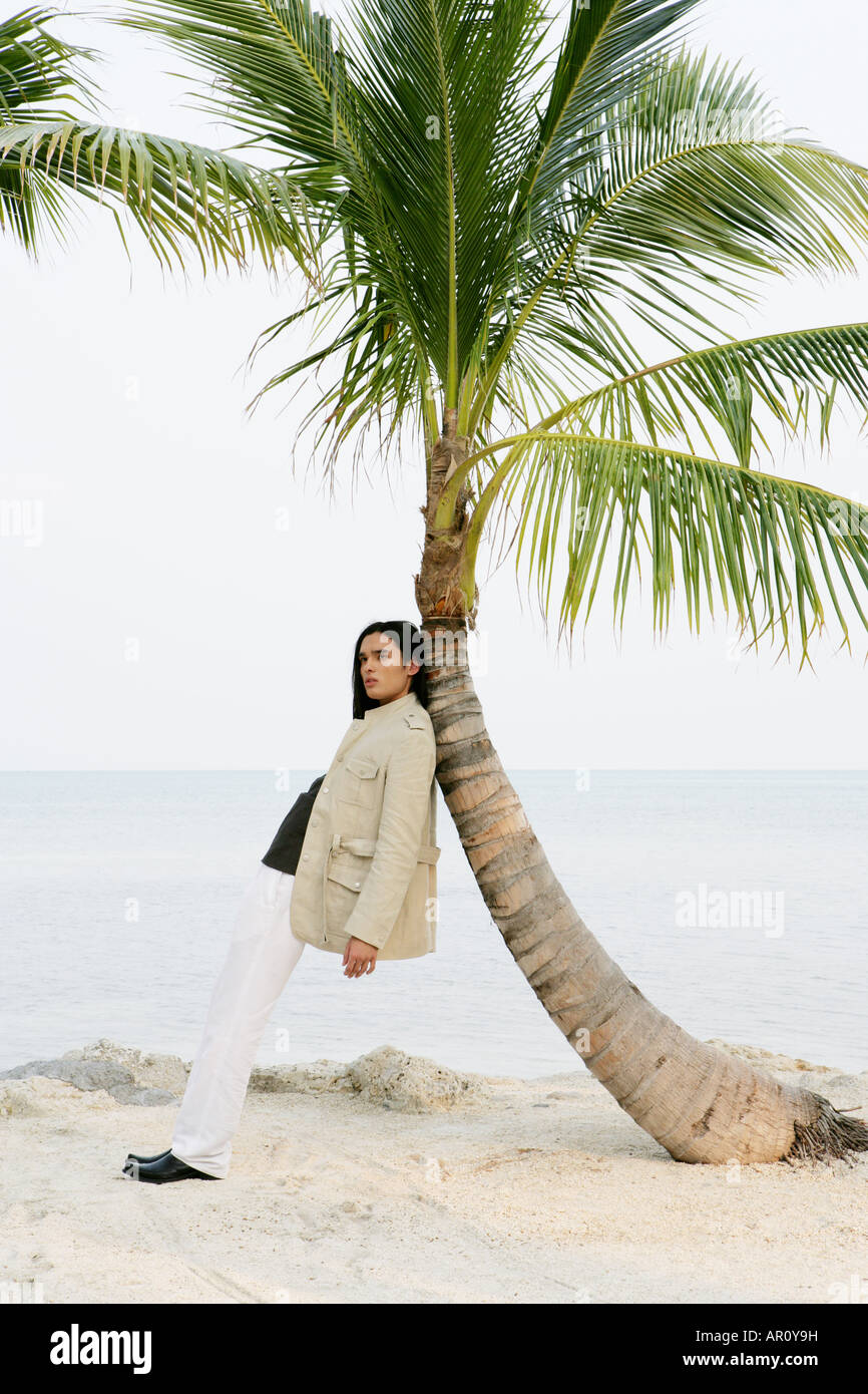 Young man leaning against palm tree Stock Photo - Alamy