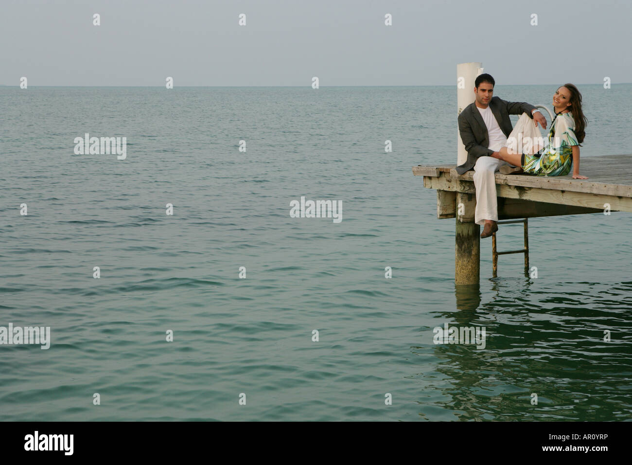 Young couple relaxing on pier Stock Photo - Alamy