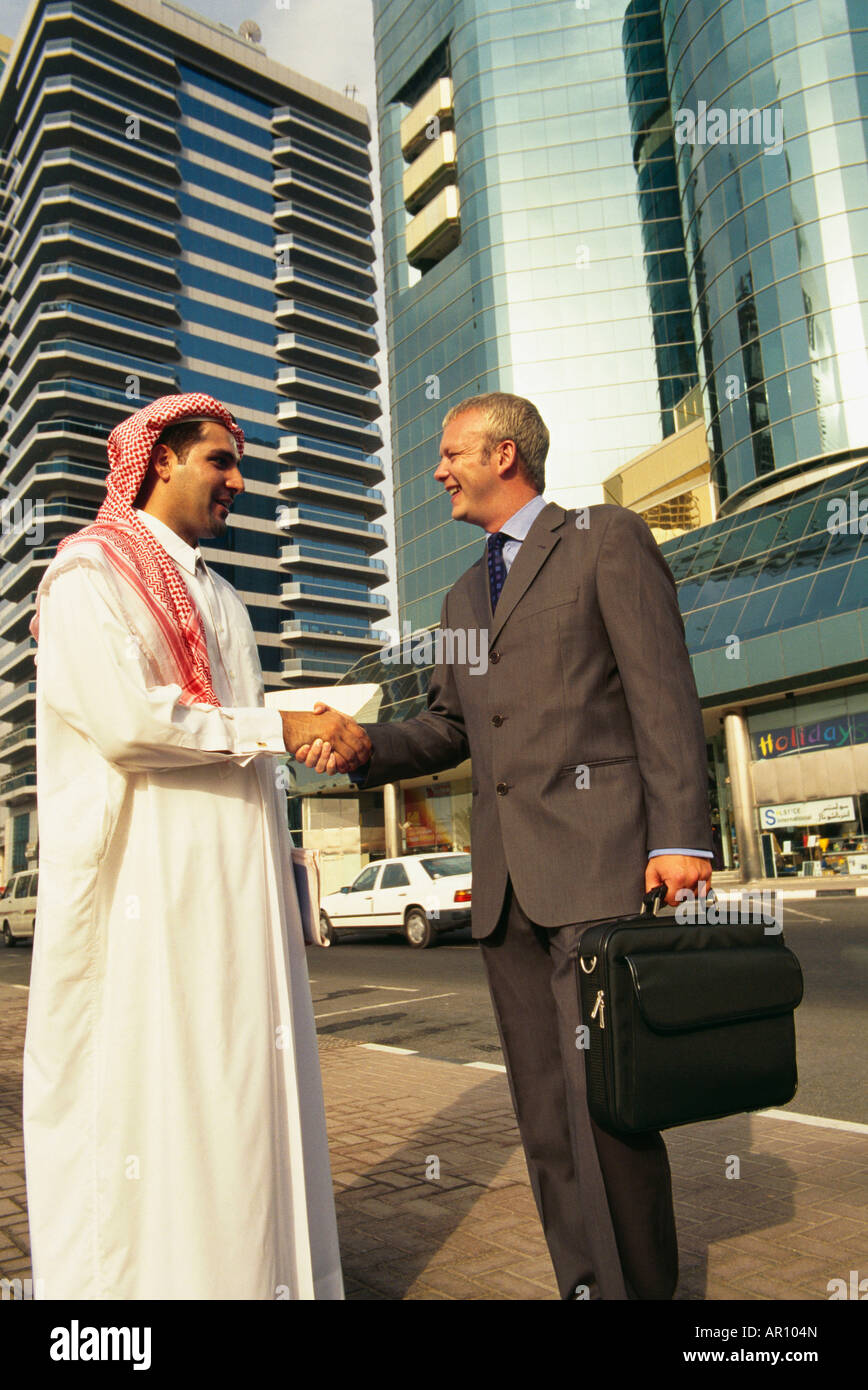 An Arab and a businessman shaking hands near a commercial complex Stock ...