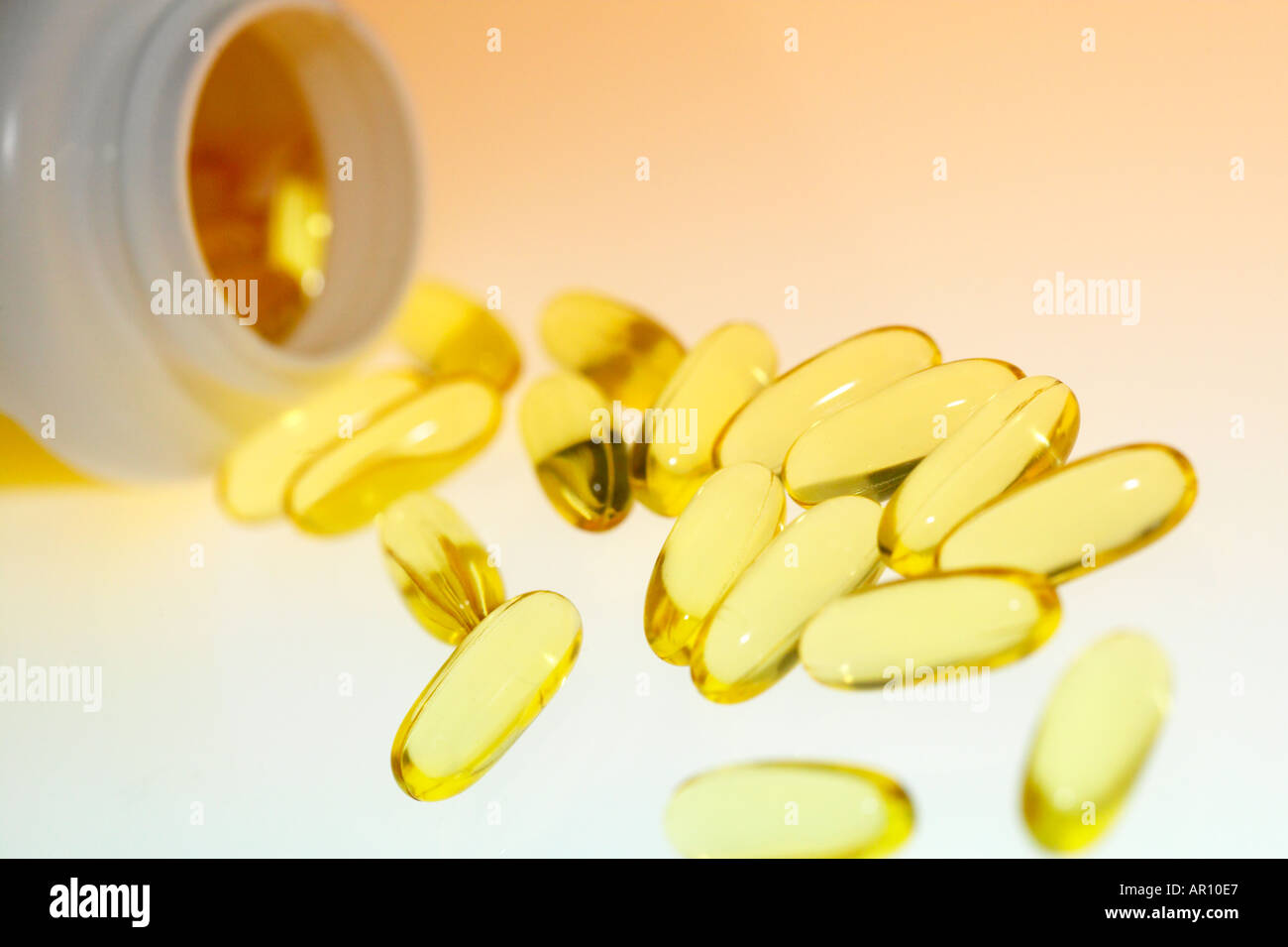 Fish oil capsules spilling from a container Stock Photo - Alamy