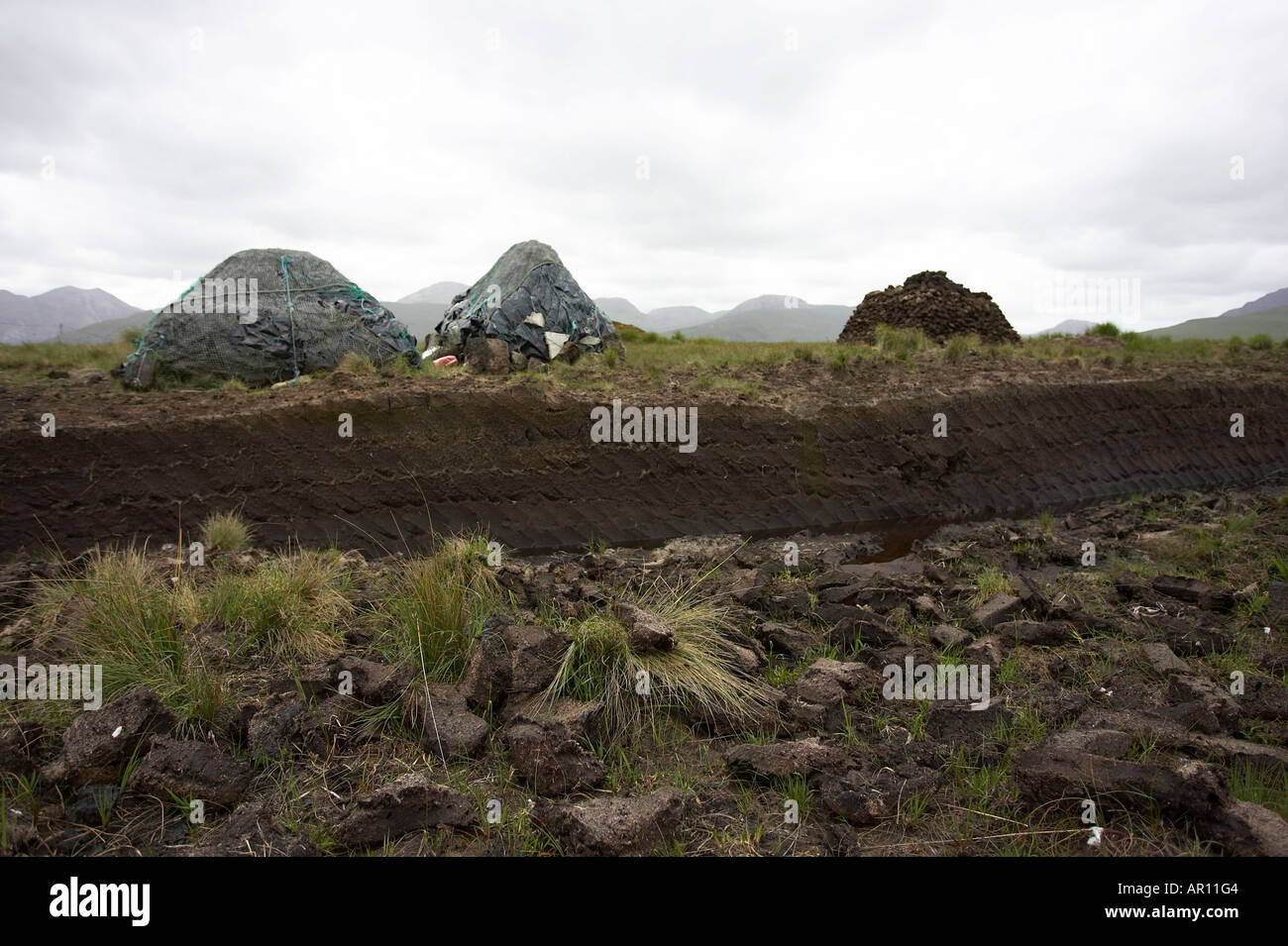 mounds of Turf peat cut next to the cut seam in a peat bog in Connemara ...