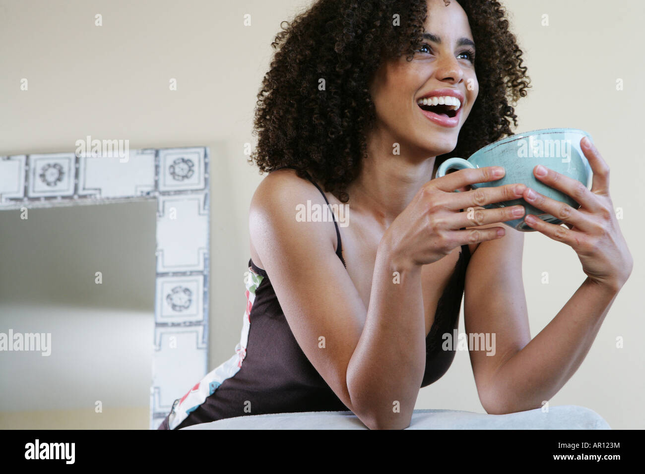 Young woman smiling holding a mug Stock Photo - Alamy