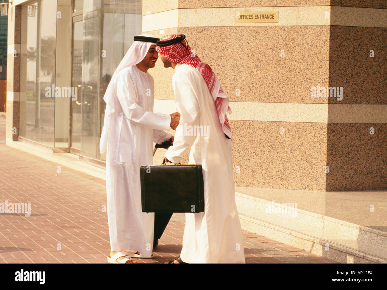 Two Arabs greet each other near the office entrance Stock Photo - Alamy