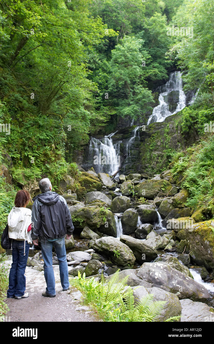 female and male tourists look at Torc Waterfall near Killarney County ...