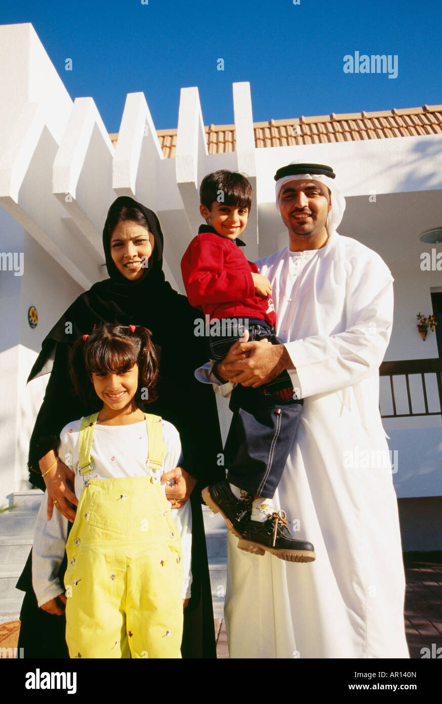 An Arab family stands outside their house and pose in front of the ...