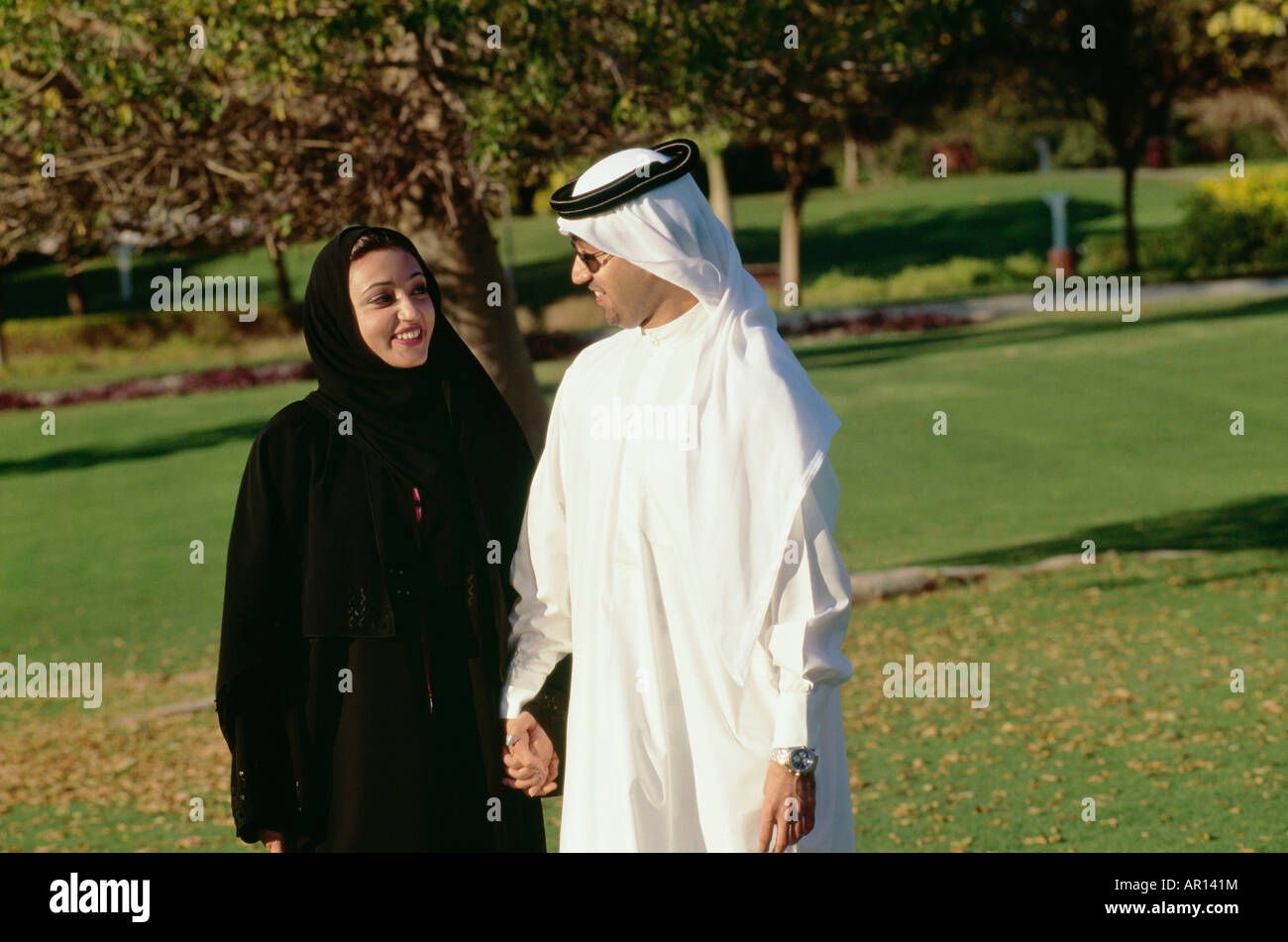 Side view of an Arab couple holding hands and taking a stroll in the ...