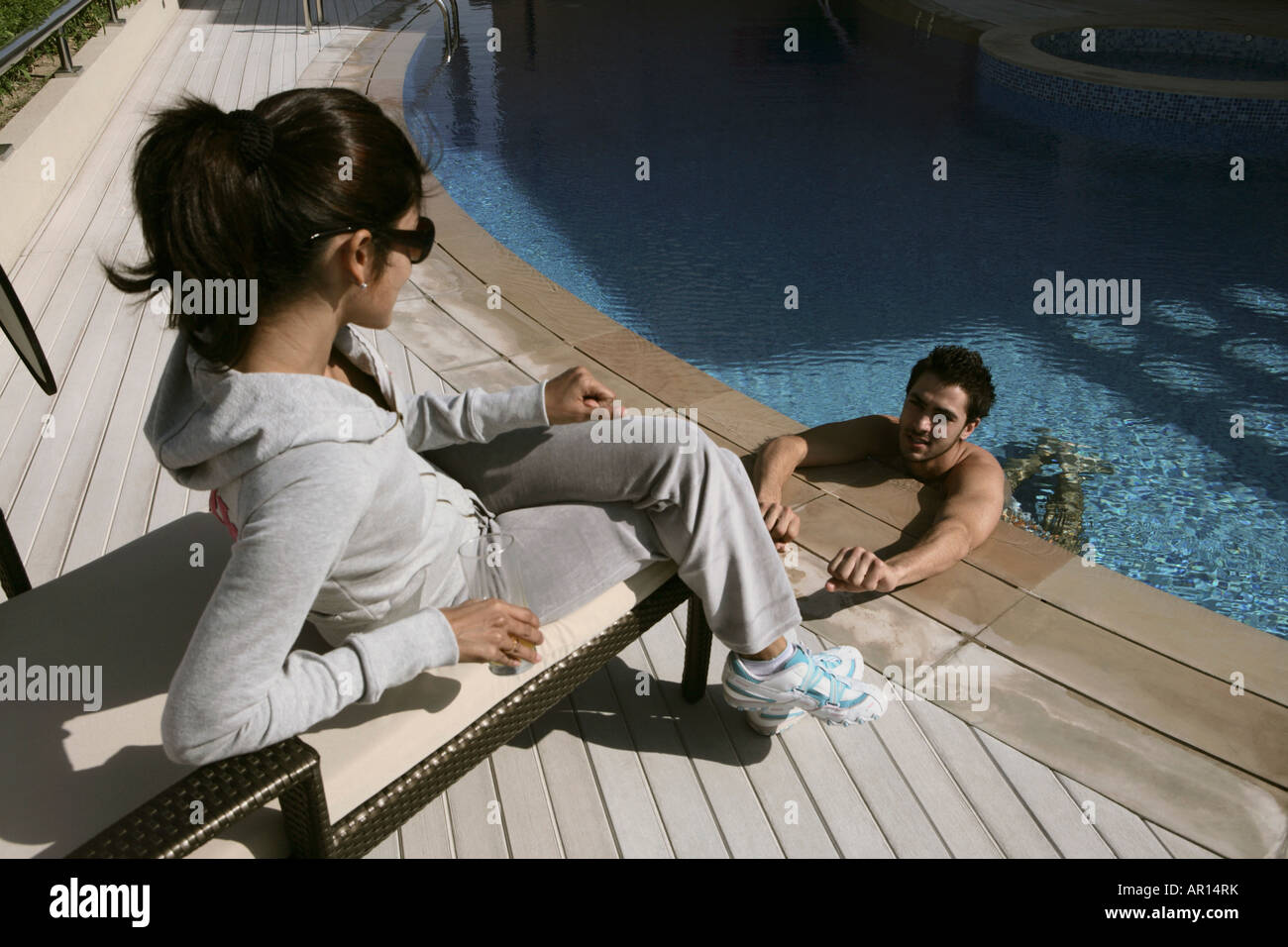 Young lady looking at man in a swimming pool Stock Photo - Alamy
