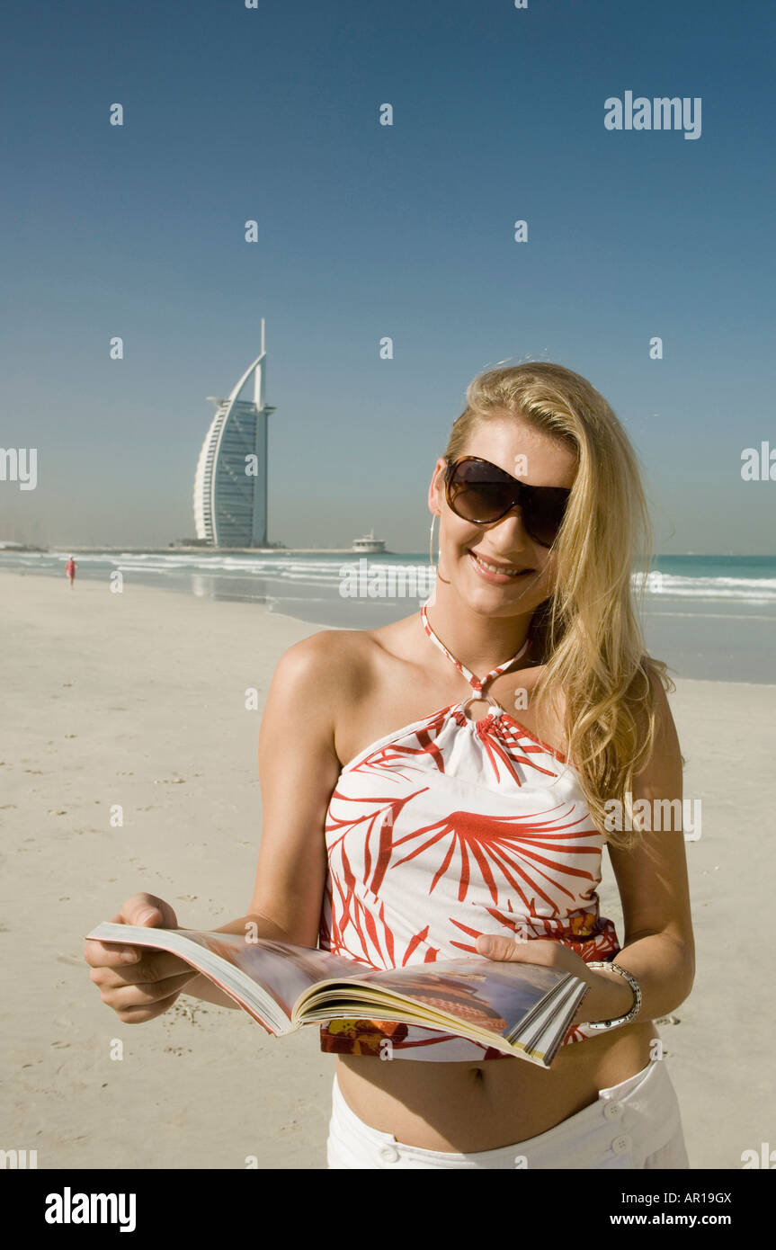 Young lady with guide book in front of the famous landmark of Dubai ...