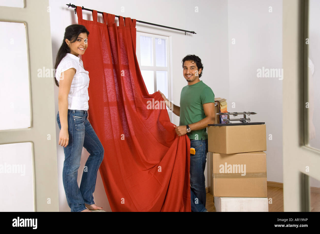 Young couple fixing the curtain on moving into a new home Stock Photo ...