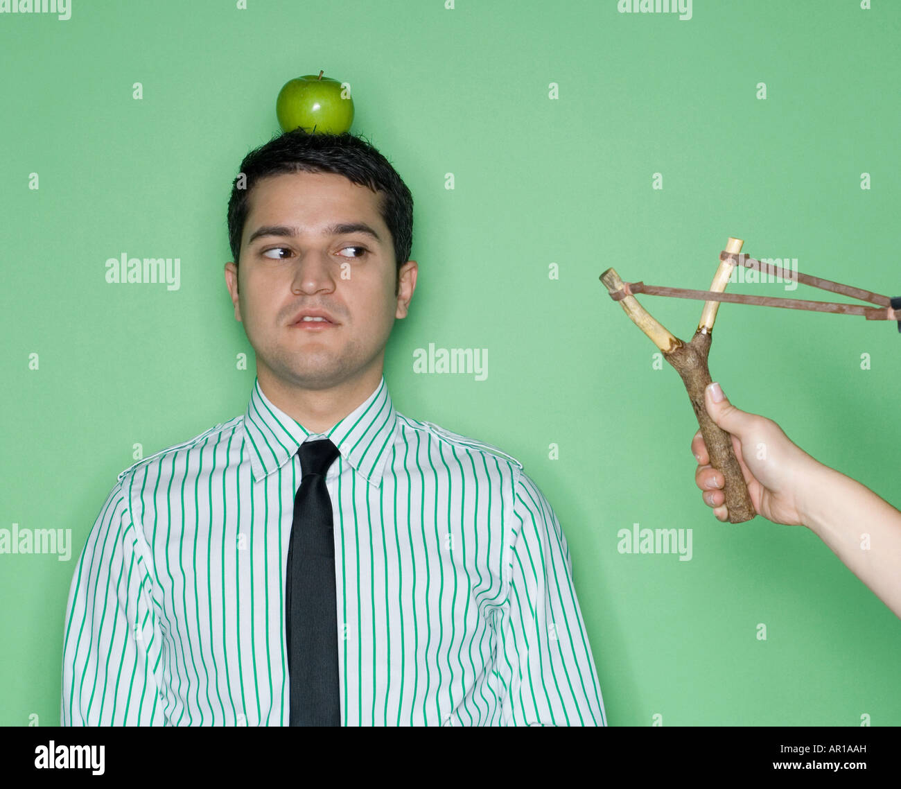 Portrait of a young man balancing a green apple on his head as a ...
