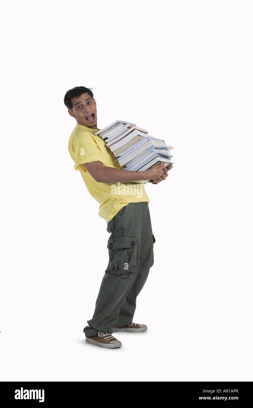 Young man carrying pile of books, portrait Stock Photo - Alamy